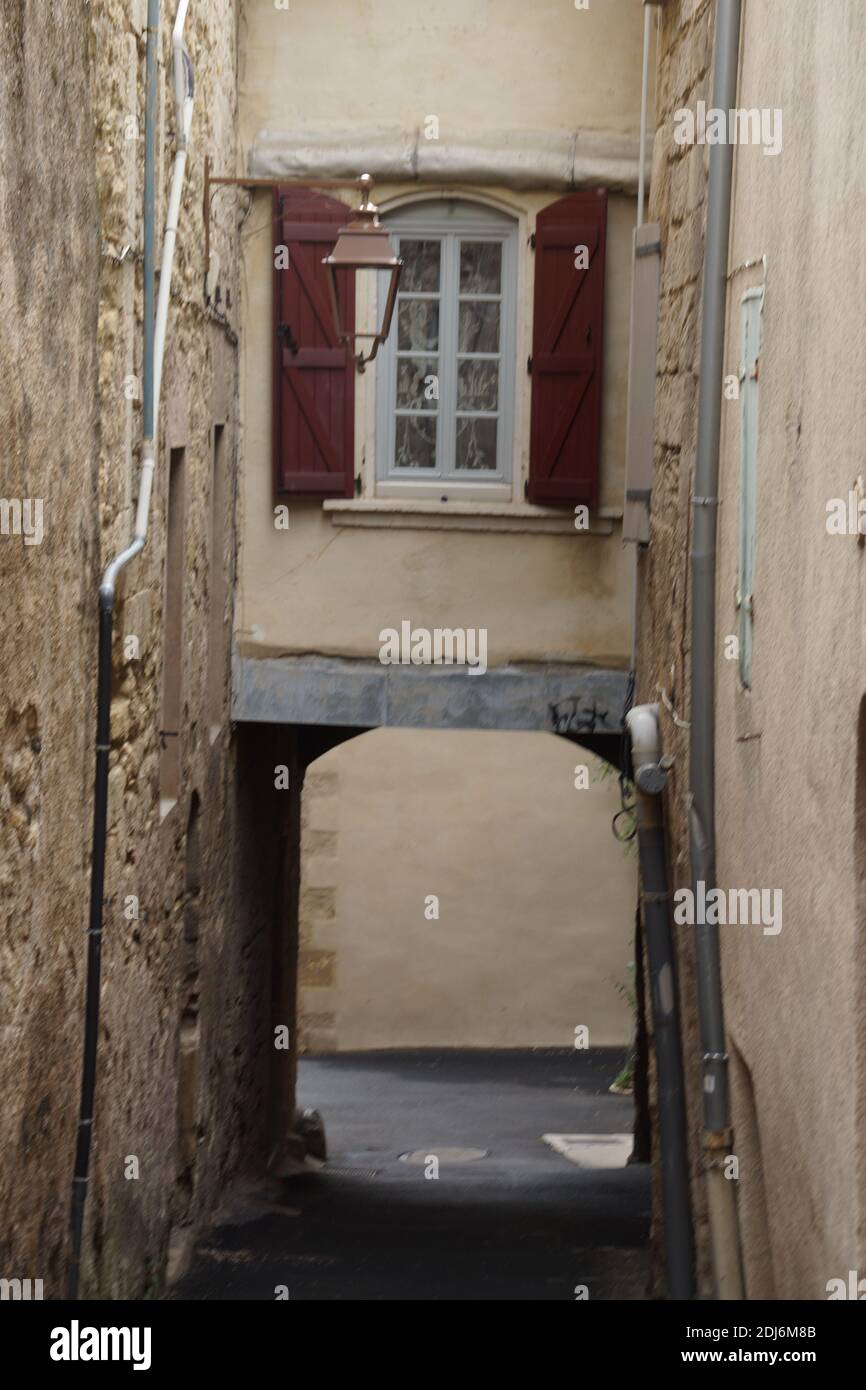 A vertical shot of a window on a building through a narrow path between ...