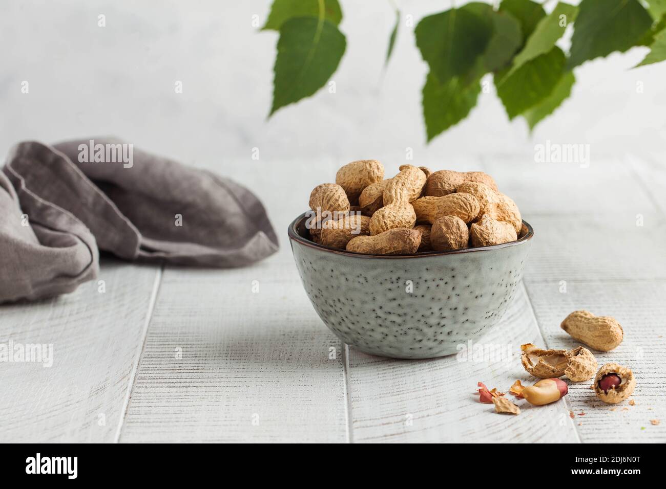 Peanuts in a shell in a gray bowl on a white wooden background with ...