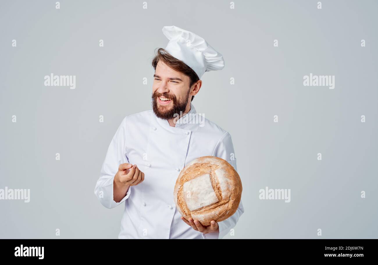 A cook in uniform and a headdress with a loaf of bread in his hand ...