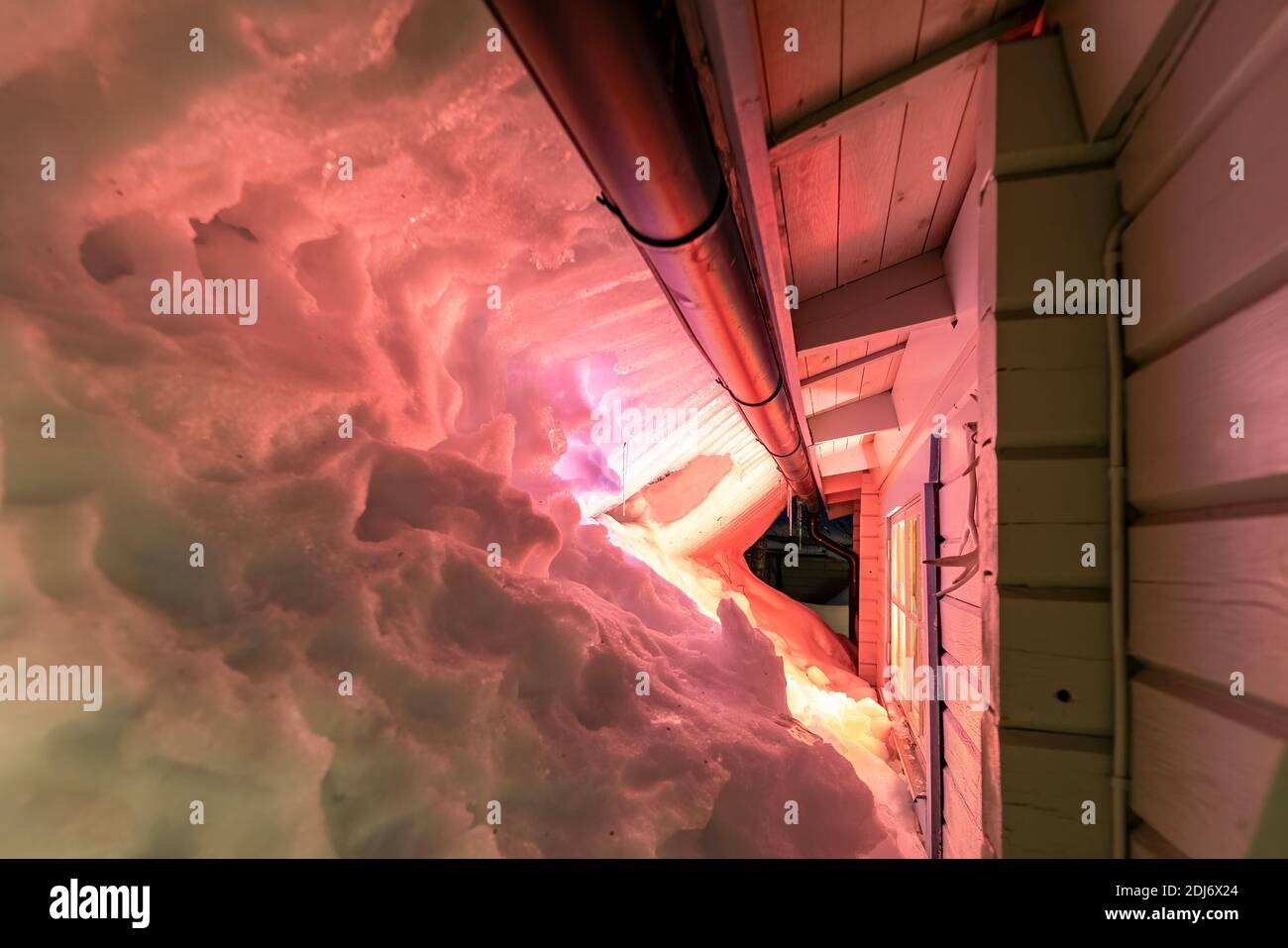 Night photo of snow drifts, slides down off the roof and freeze if form ...