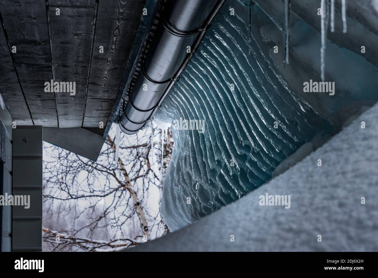 Wet melting snow drifts, slides down off the roof and freeze if form of ...