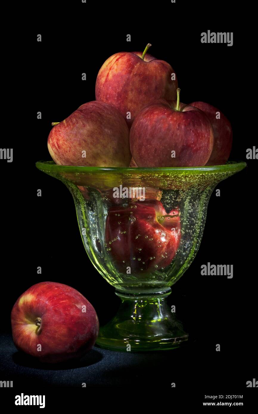 Five red apples in a green glass vase with lots of little bubbles ...