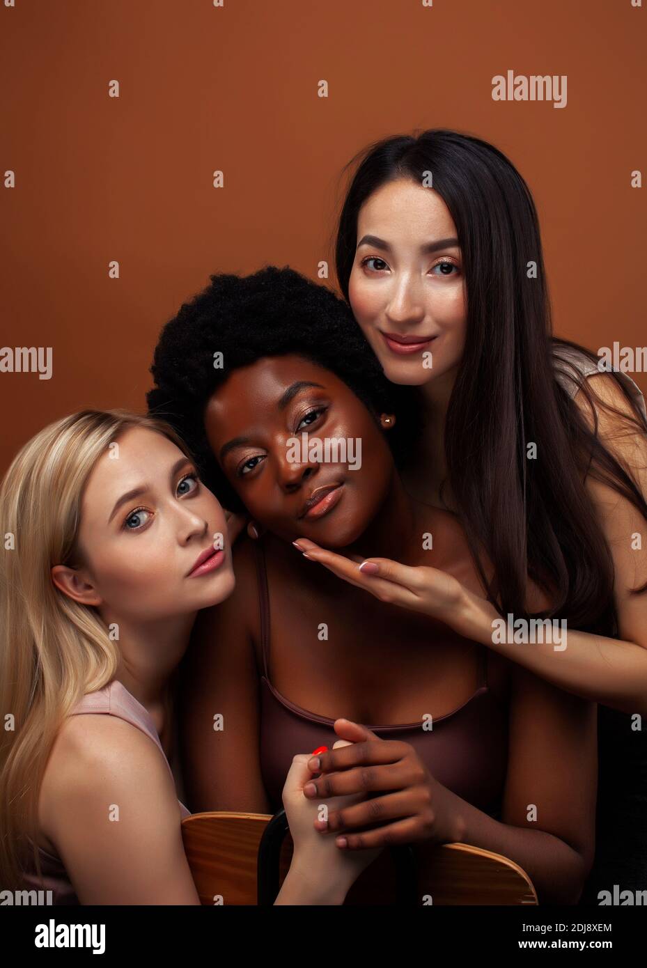 young pretty asian, caucasian, afro woman posing cheerful together on brown background ...