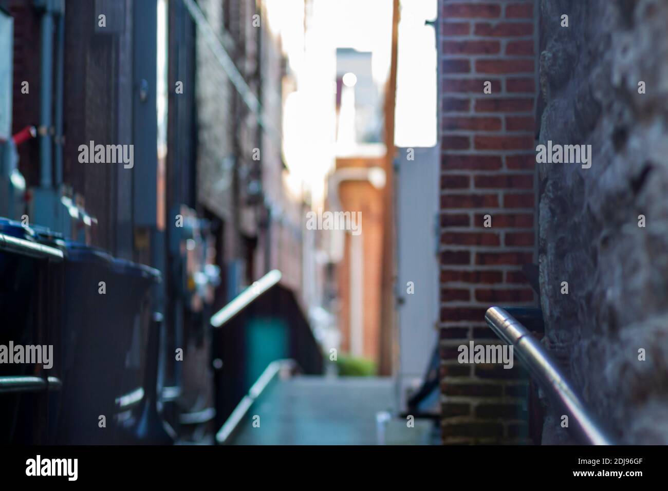 A moody abstract out of focus image of a narrow alley between brick ...