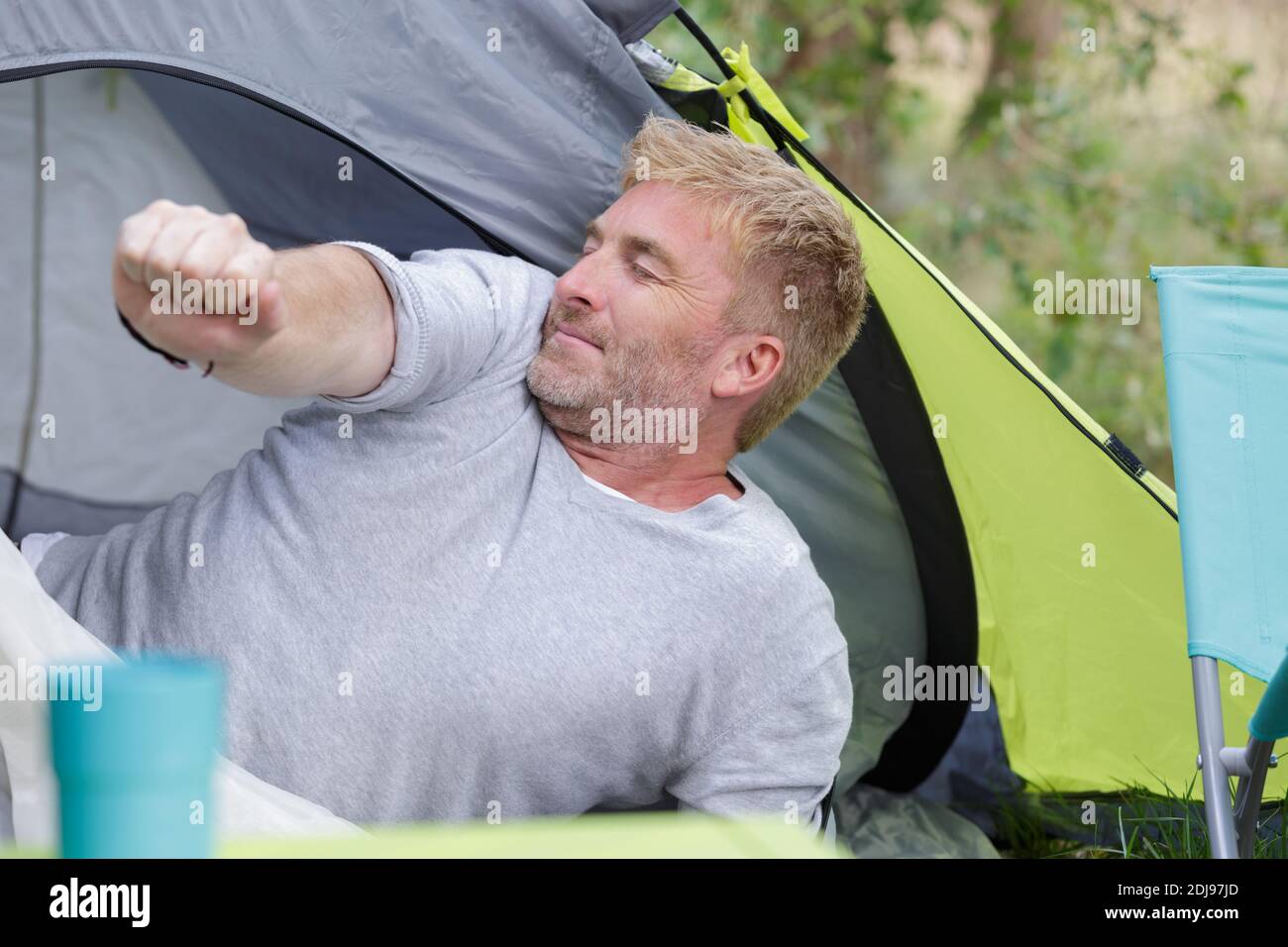 man stretches as he wakes and leans out of tent Stock Photo - Alamy