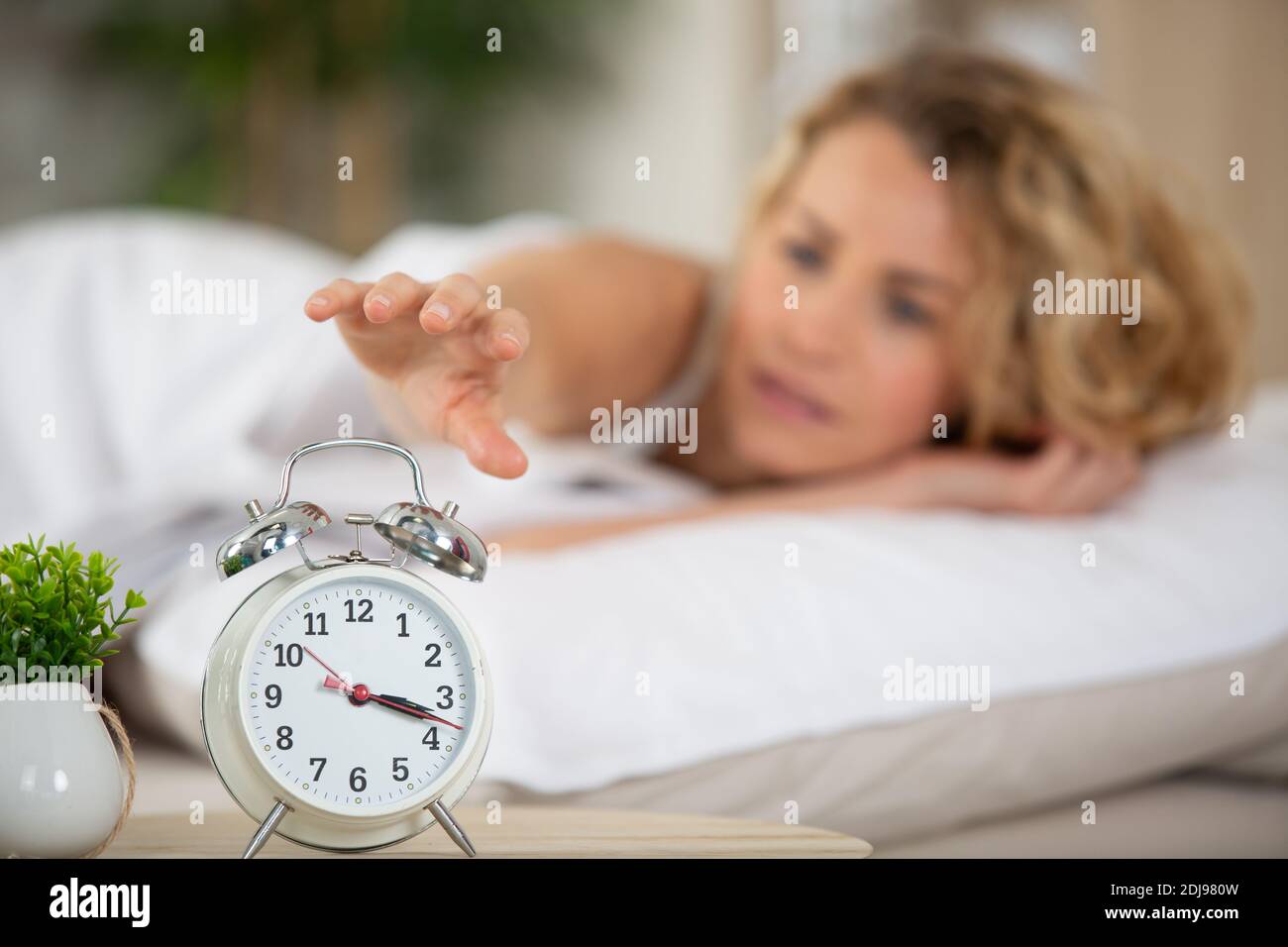 young woman is waking up with alarm clock Stock Photo - Alamy