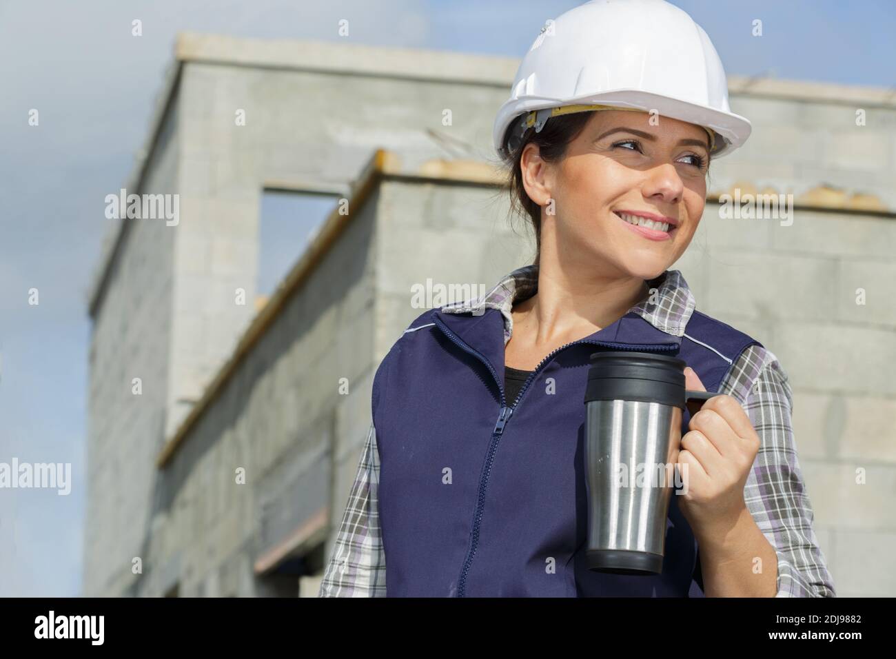 female contractor on building site holding insulated coffee cup Stock ...