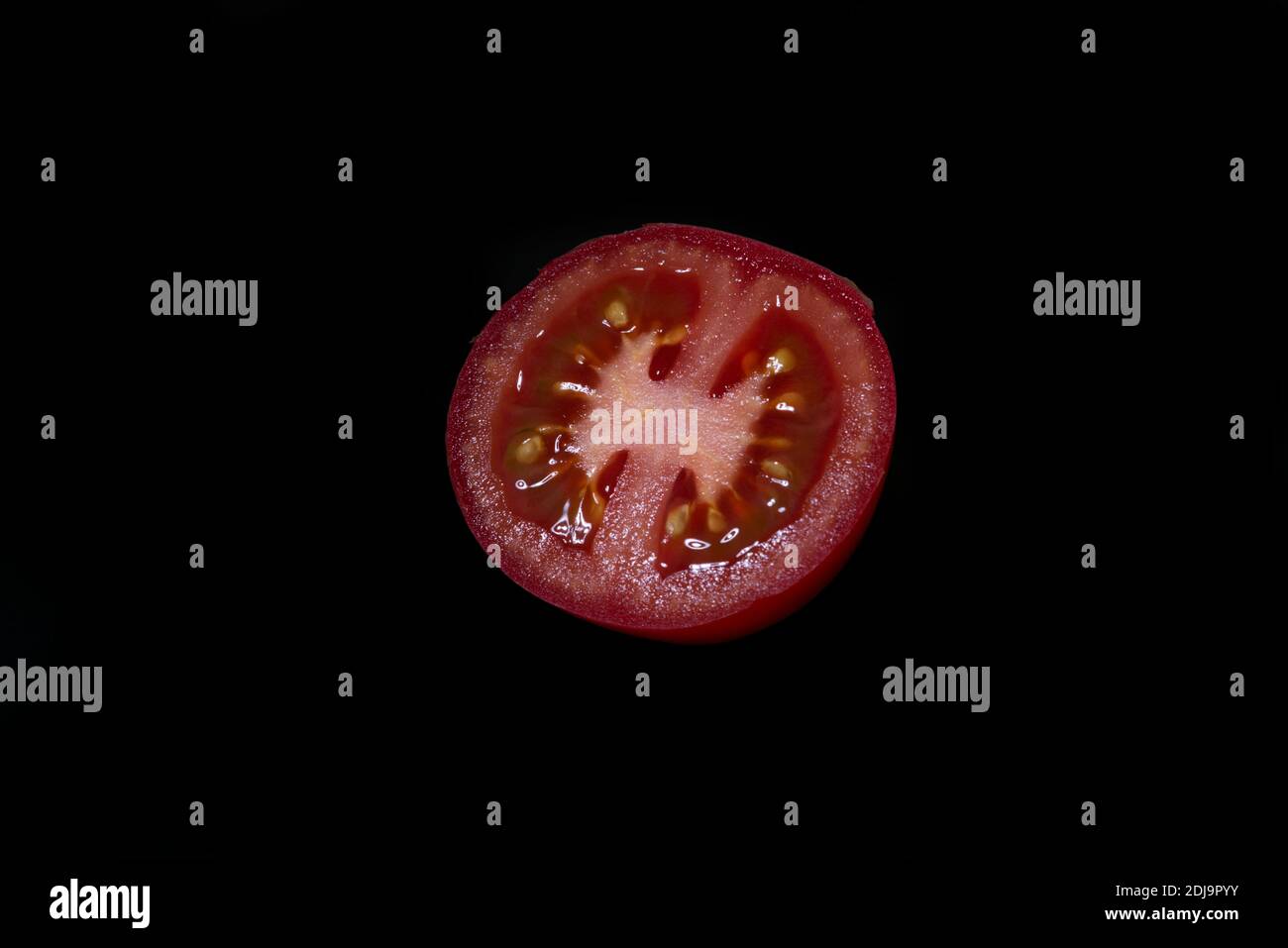 fresh half sliced tomato on black background Stock Photo - Alamy
