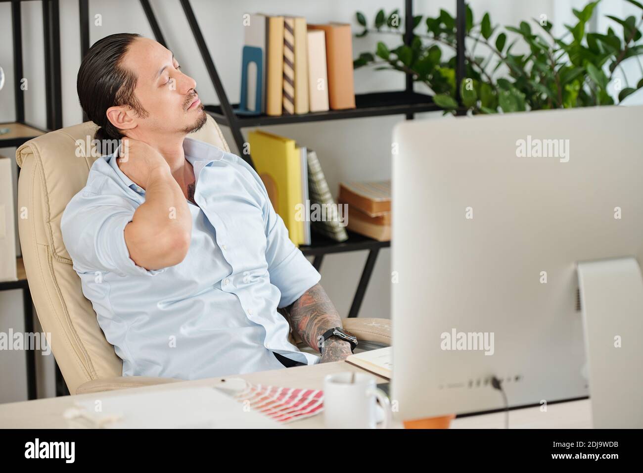 Tired graphic designer feels fatigue massaging tensed muscles of stiff ...