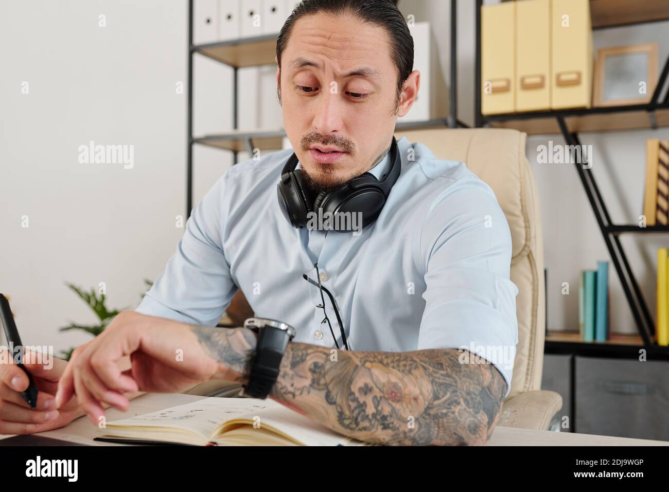 Graphic designer checking watch on his wrist after working on project ...
