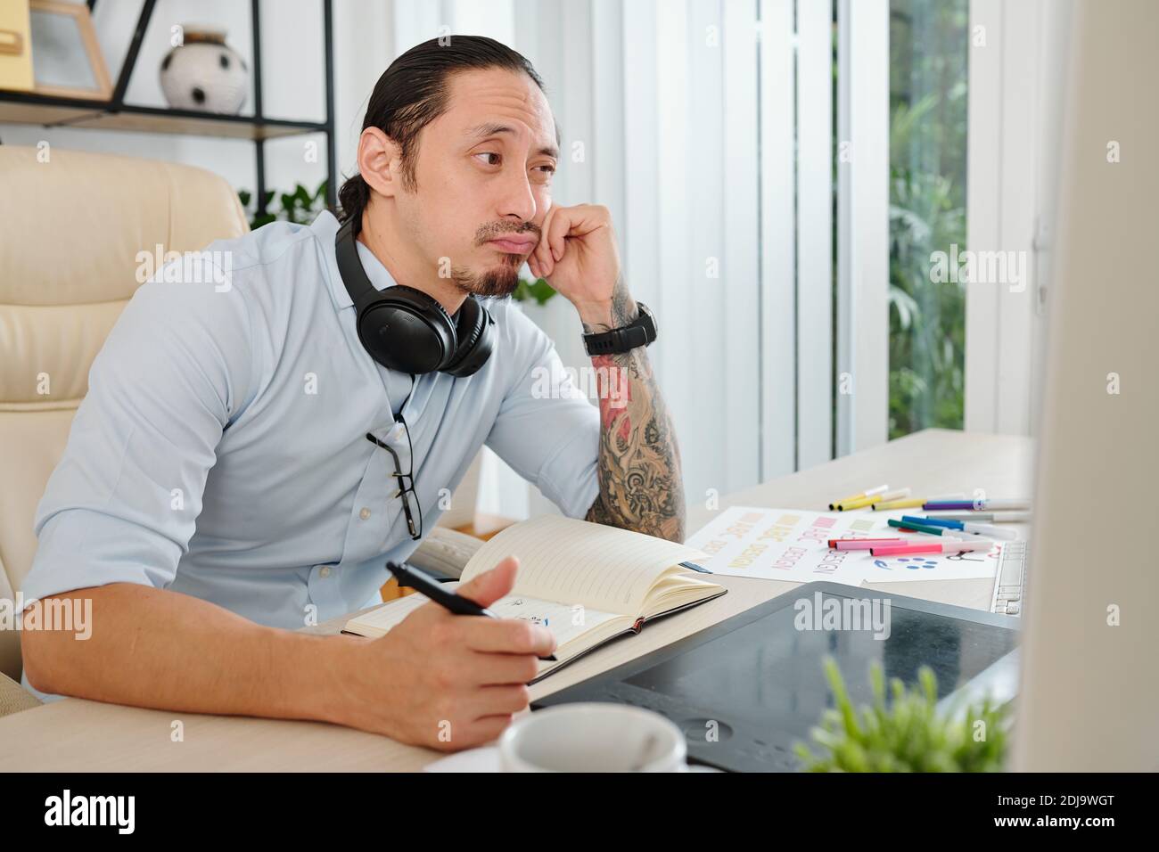 Pensive bored graphic designer reading brief from client and figuring ...