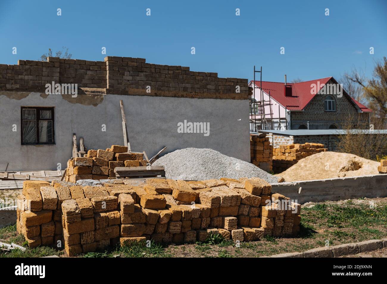 A pile of bricks lies in front of the house that is being built Stock ...