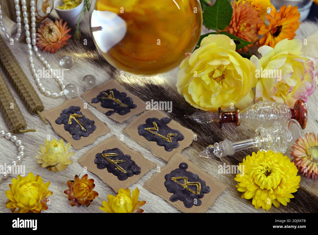 Still life with black runes, magic ball, yellow flowers, candles and ...