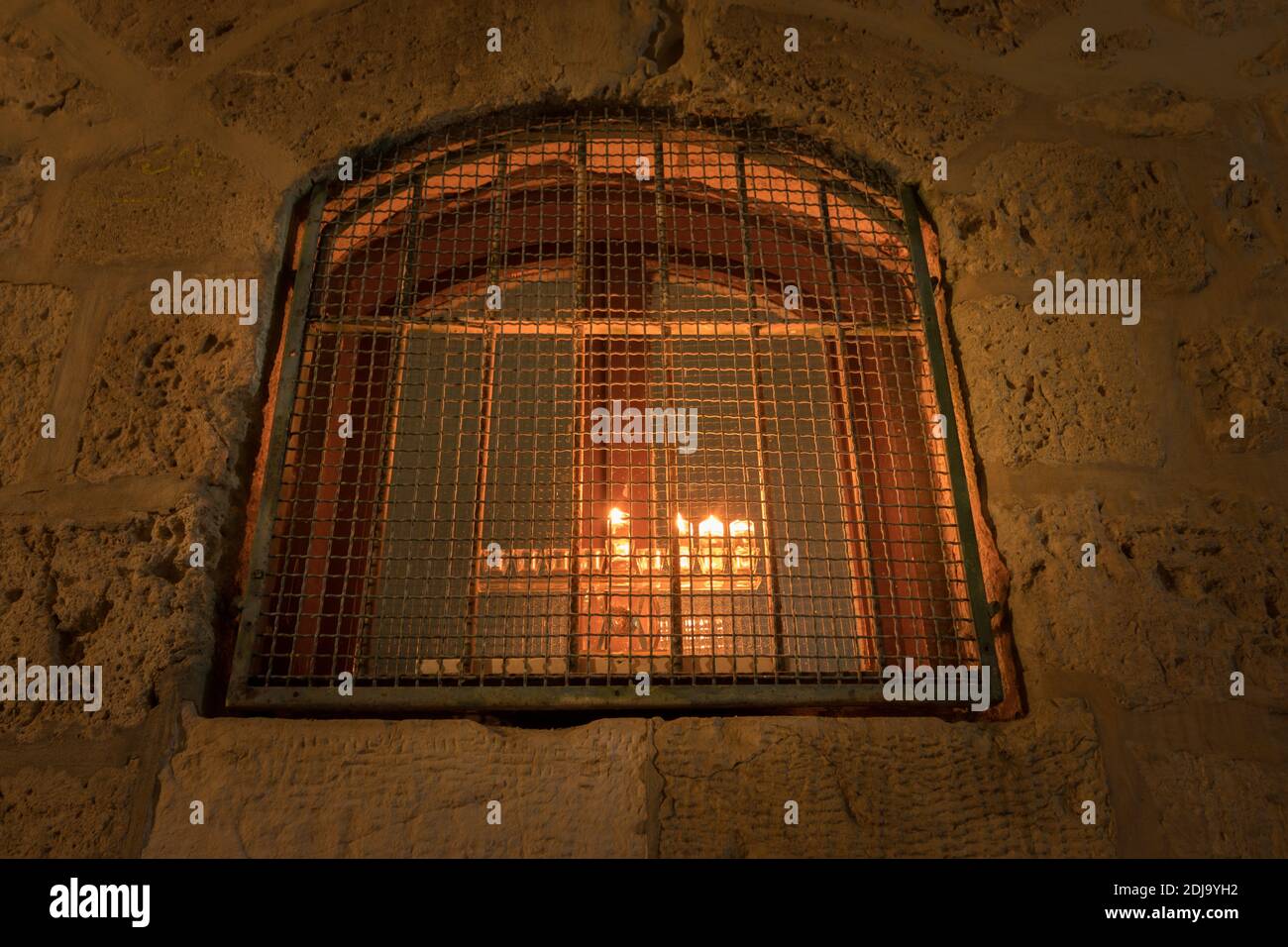 A menorah is lit inside a window, in an ancient house in the Jewish ...