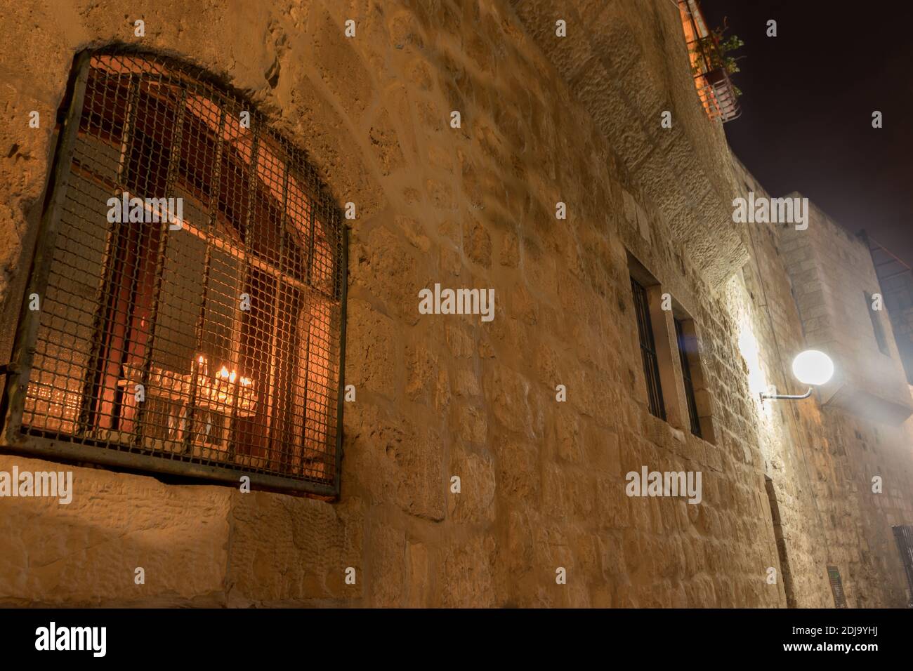 A menorah is lit inside a window, in an ancient house in the Jewish ...