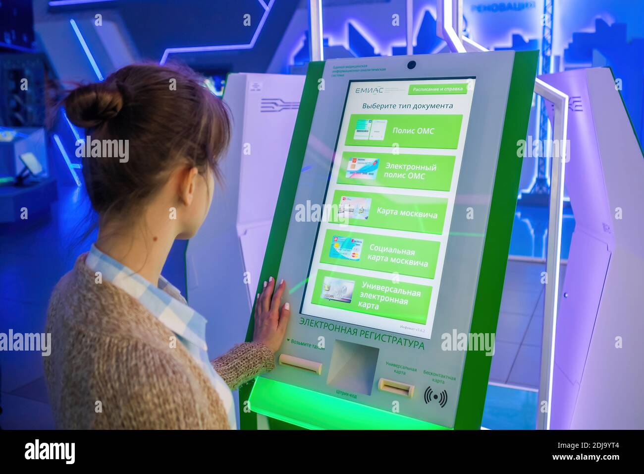 Woman using interactive touchscreen green kiosk at modern museum or ...
