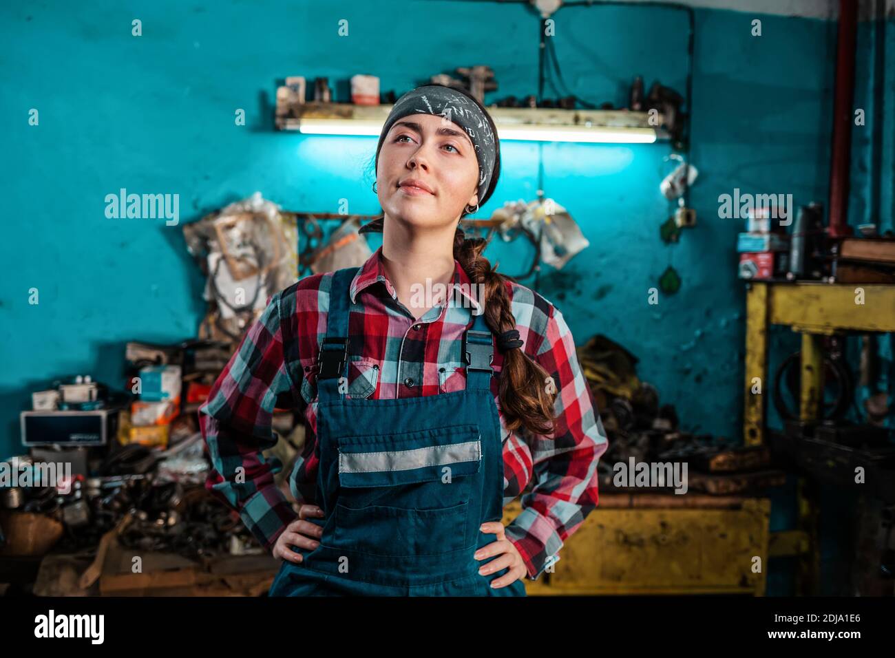 Portrait of a young beautiful female mechanic in uniform who poses with ...