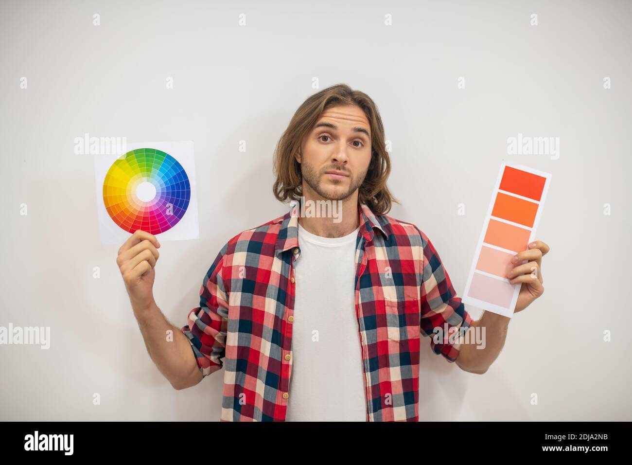 Young man holding color palette and looking uncertain Stock Photo - Alamy
