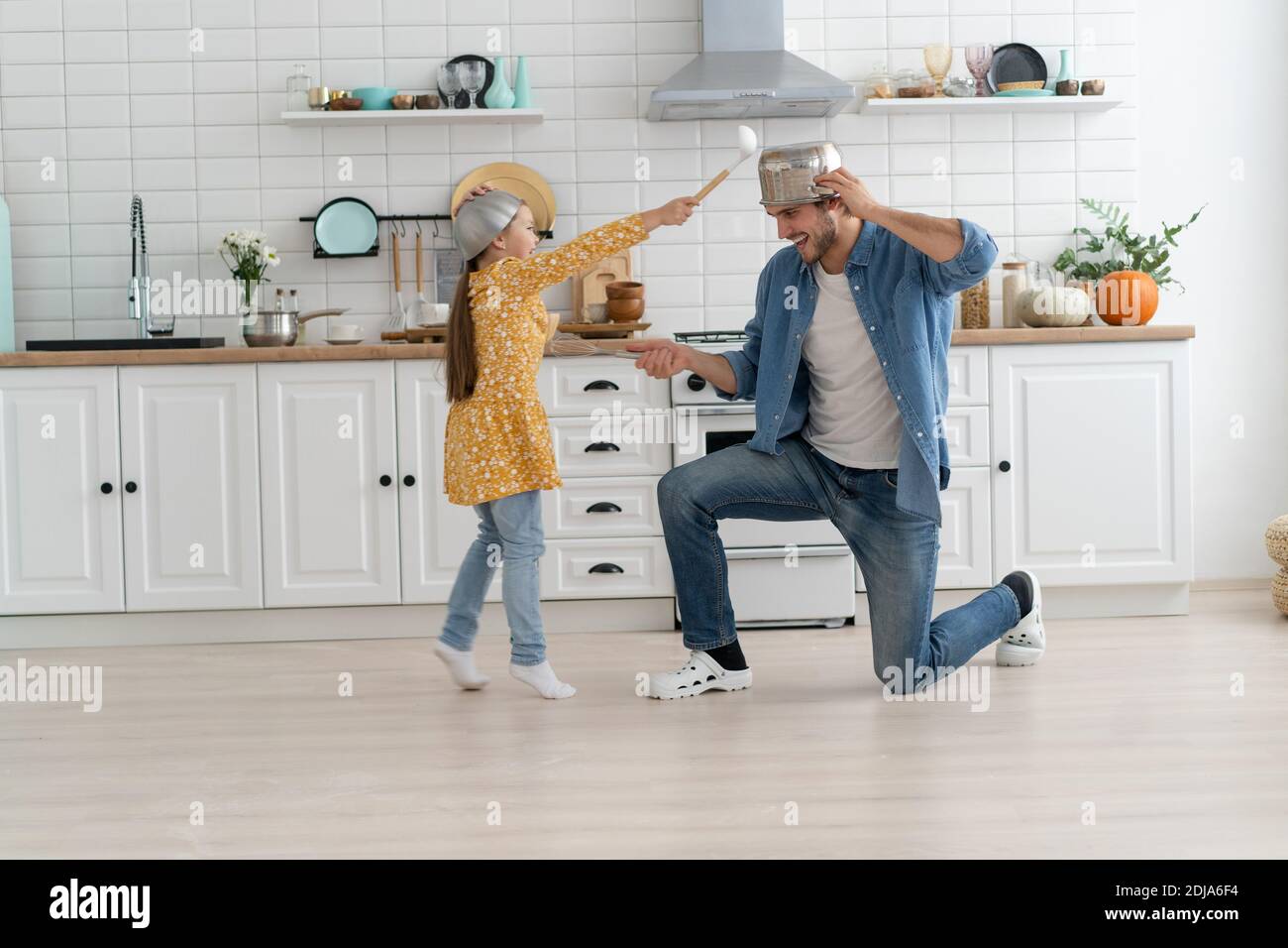 Caucasian father and daughter enjoy battle funny activity in kitchen ...