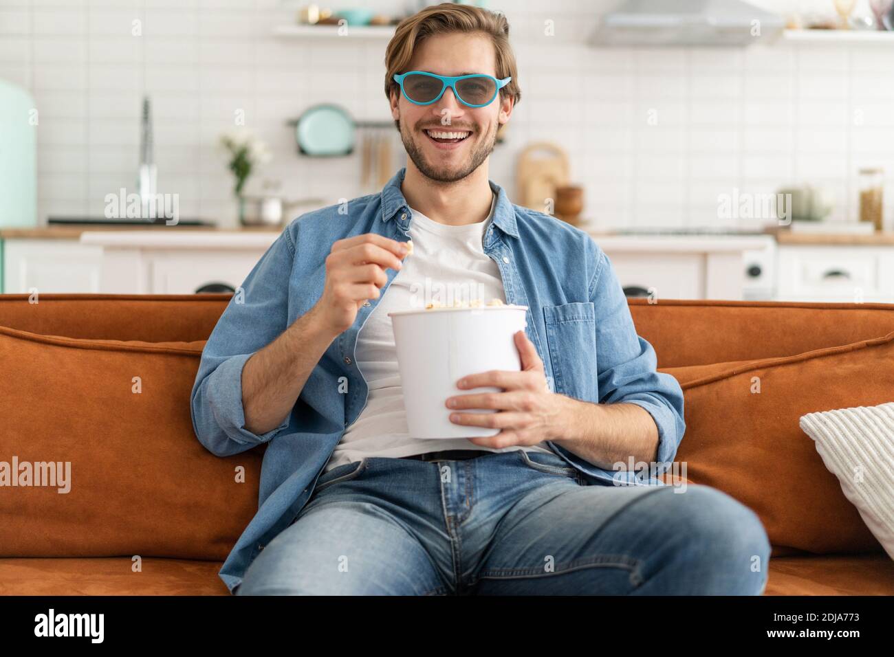 Young man with popcorn in hands watching tv at home Stock Photo - Alamy