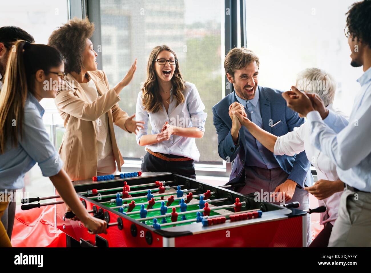 Coworkers playing table football on break from work Stock Photo - Alamy