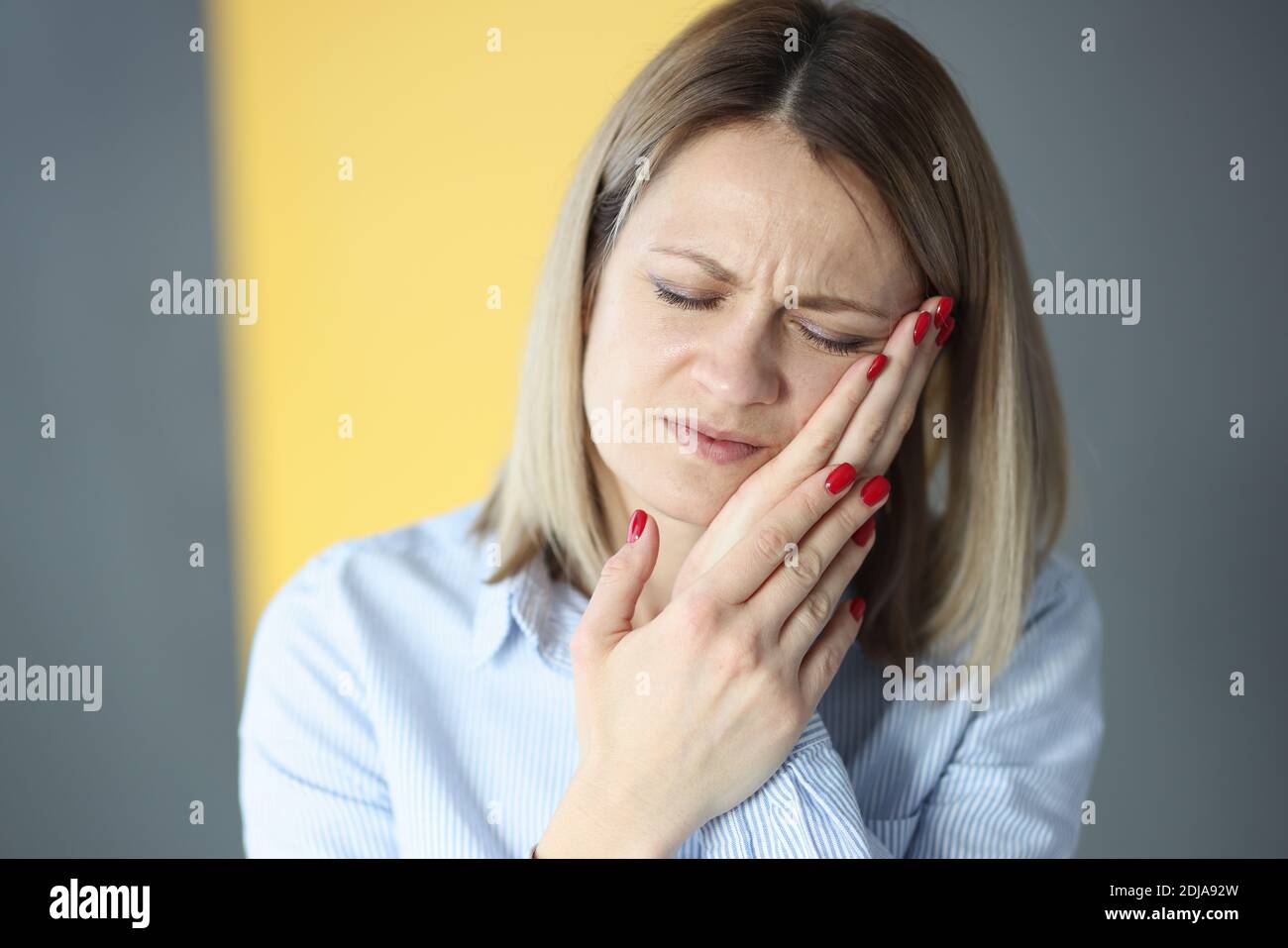 Young woman closing eyes and holding cheek with hand Stock Photo - Alamy