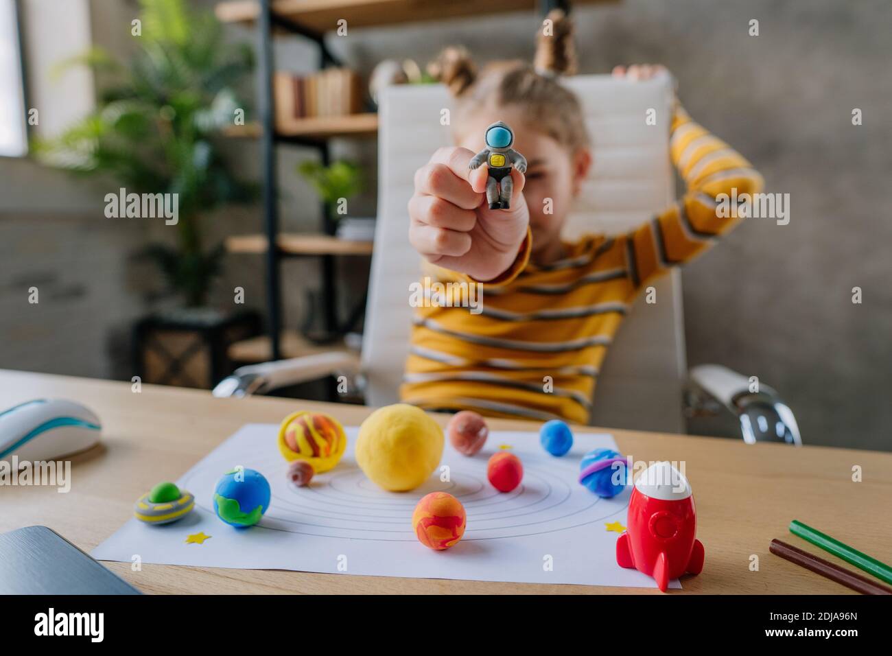 8 years old girl study Solar system sitting at the desk in the room ...