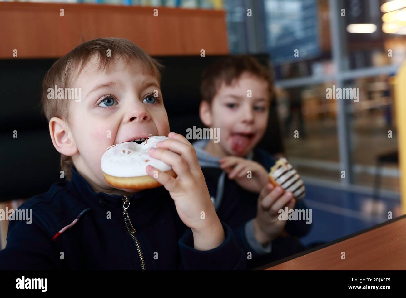 Children eating donuts at table in cafe Stock Photo - Alamy
