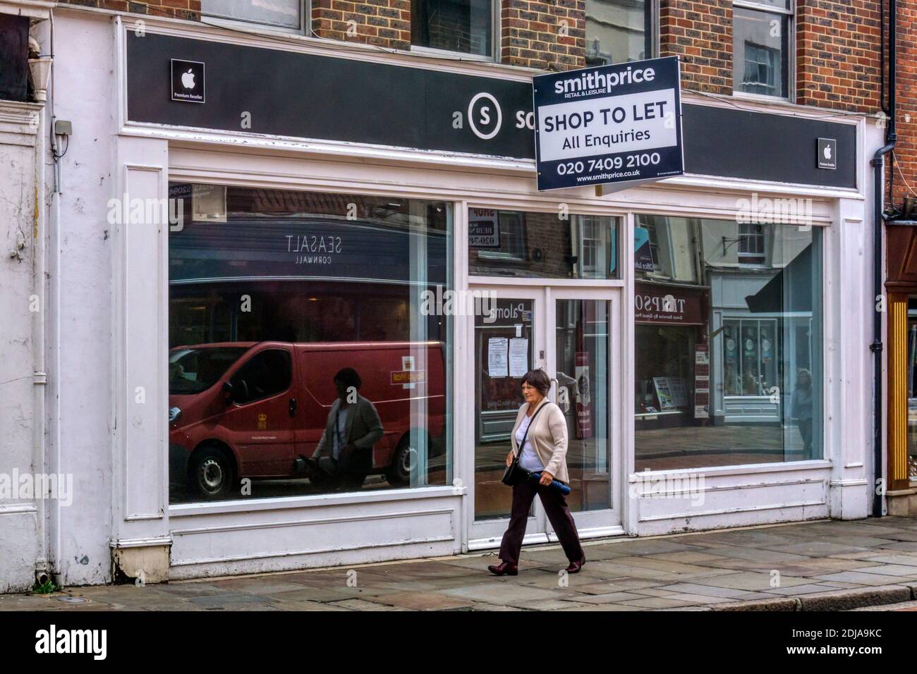Woman walking past empty shop to let in Chichester Stock Photo - Alamy
