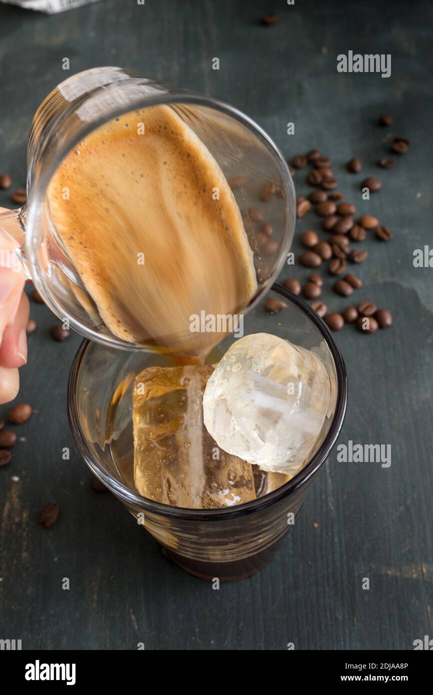Coffee glass being dropped into a coffee cup full of ice cubes over a ...