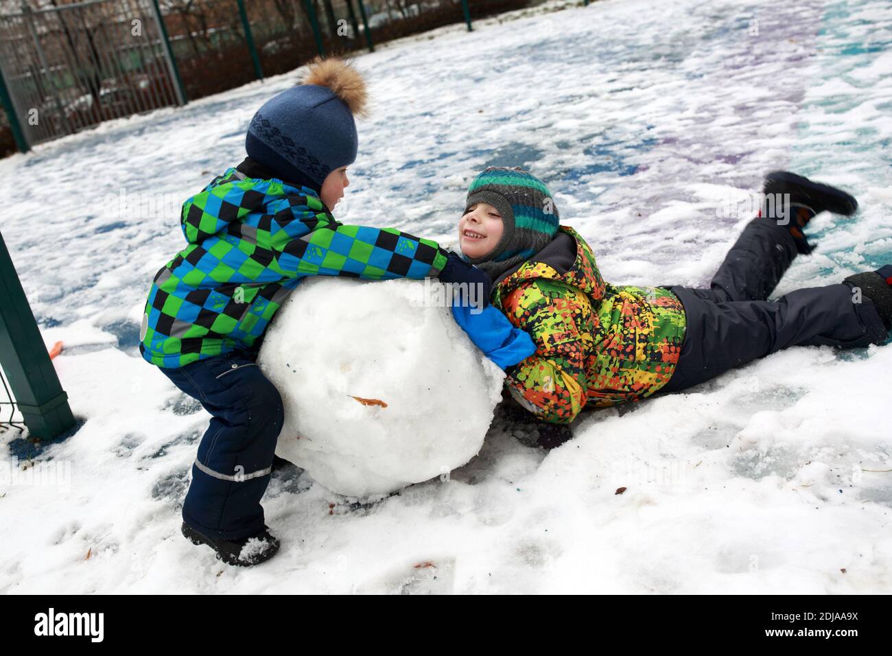 Brothers making snowman at a playground in winter Stock Photo - Alamy