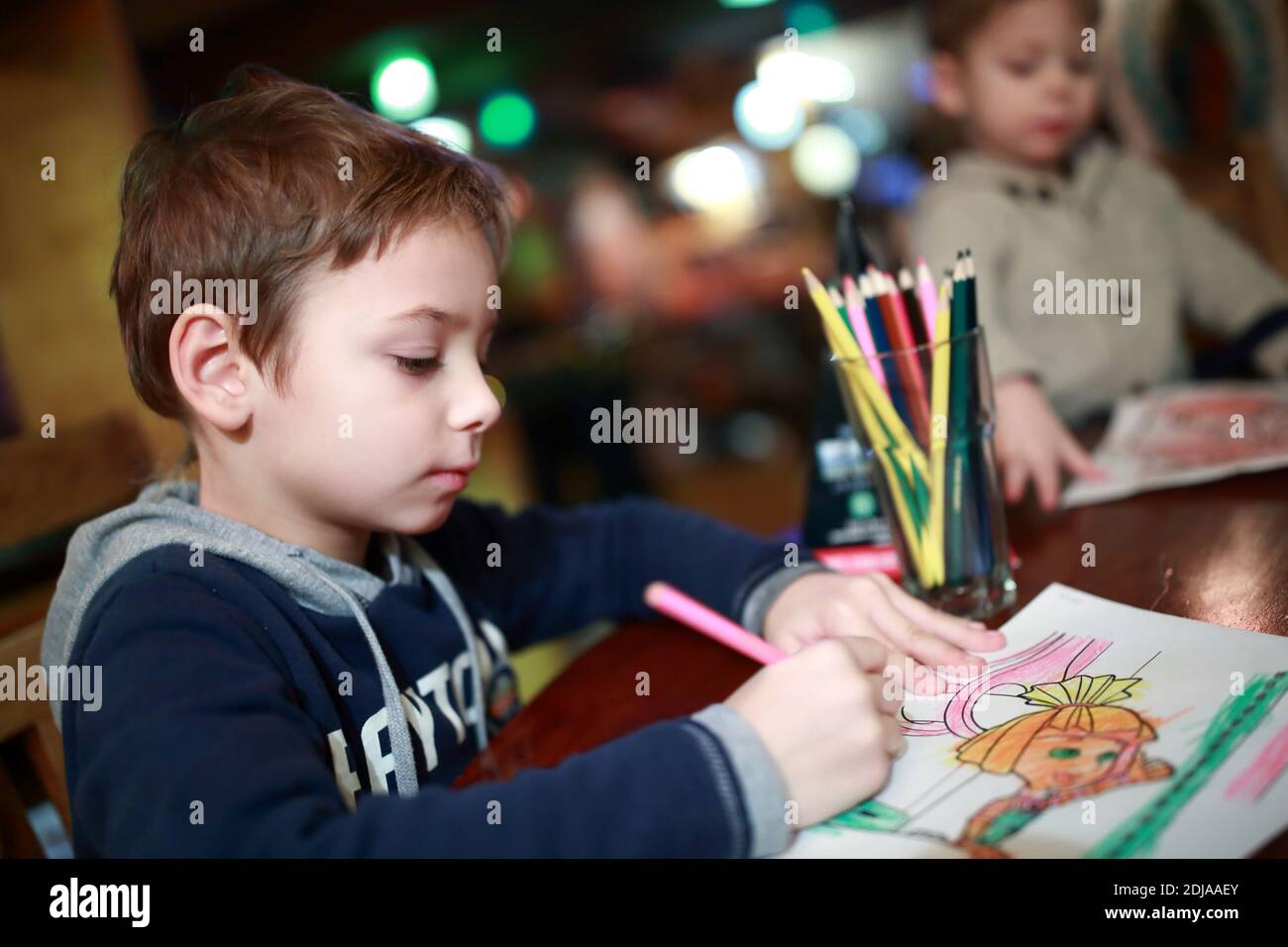 Child drawing at table in a cafe Stock Photo - Alamy