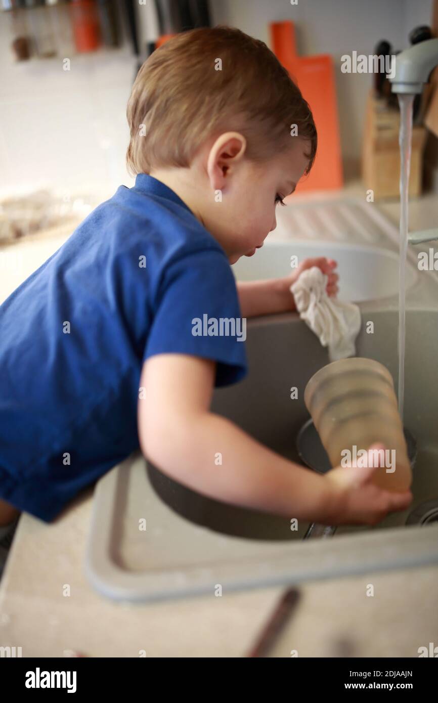 Kid washing dishes in kitchen at home Stock Photo - Alamy