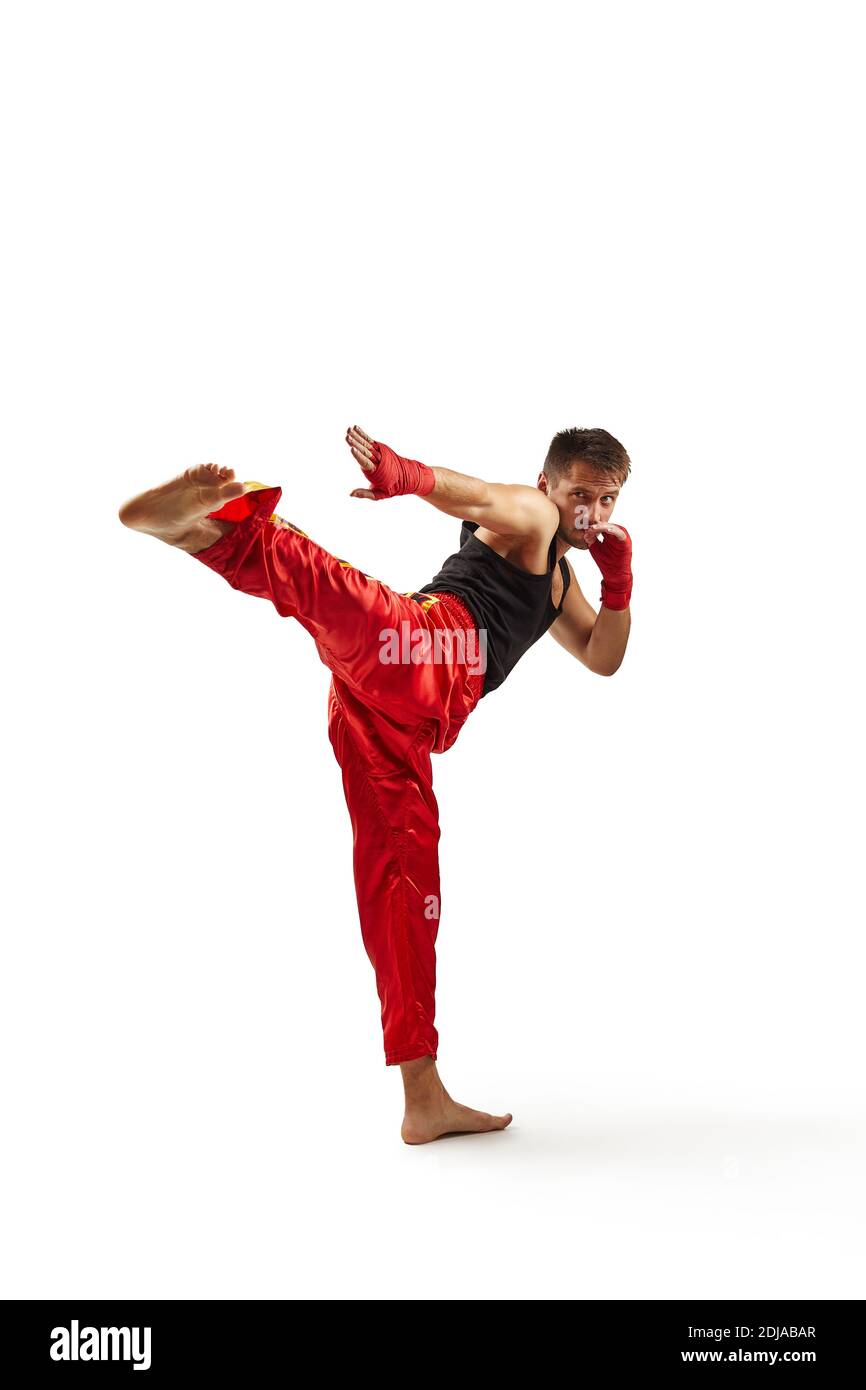 Athletic man in red sports bandages on his hands making kick during ...