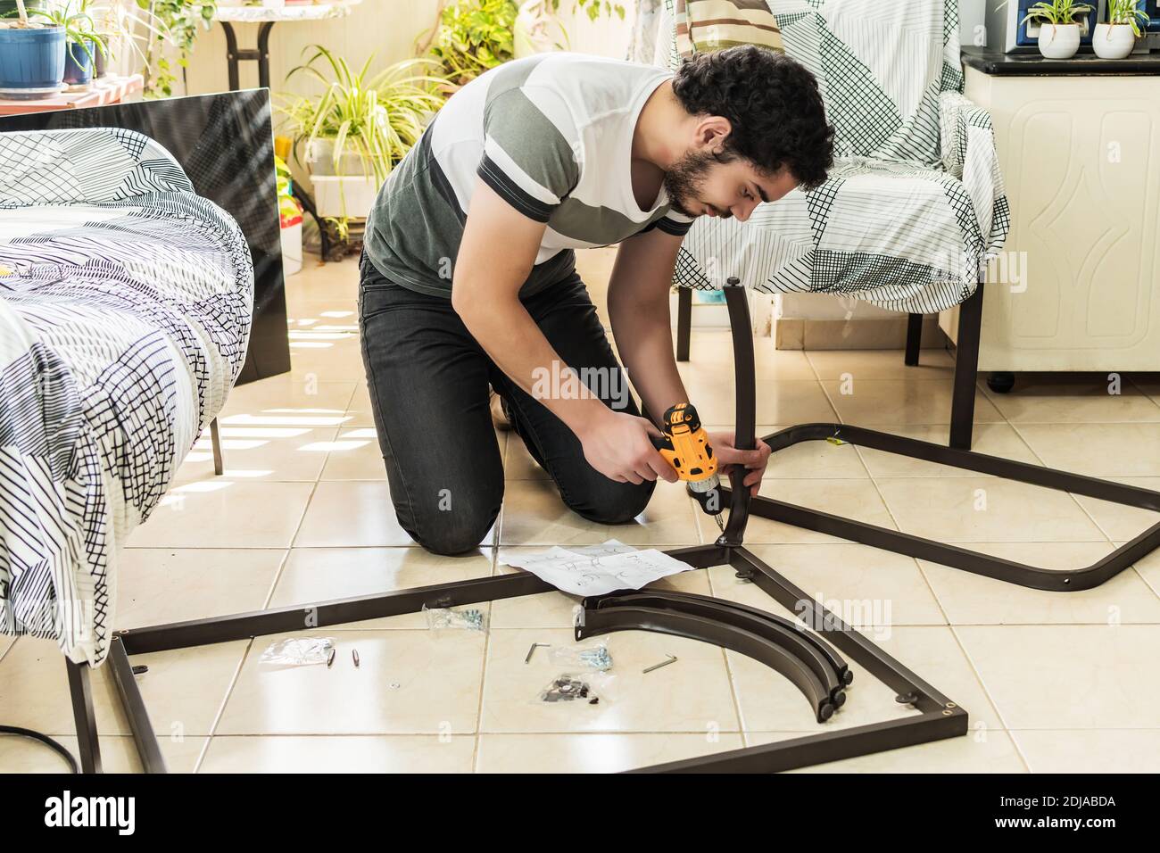 A Caucasian man repairing a table with tools in the living room of his ...