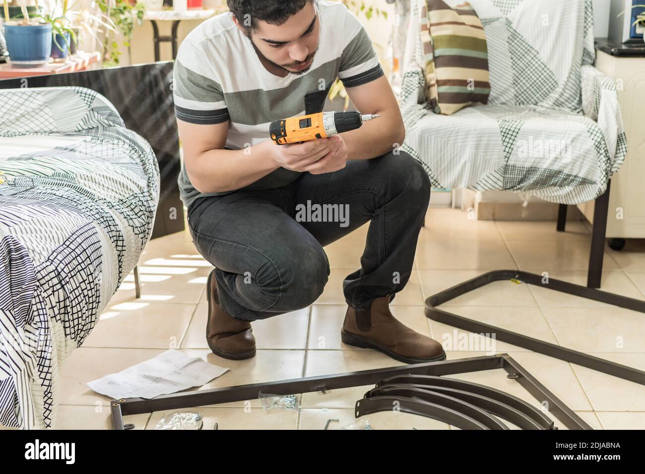 A Caucasian man repairing a table with tools in the living room of his ...