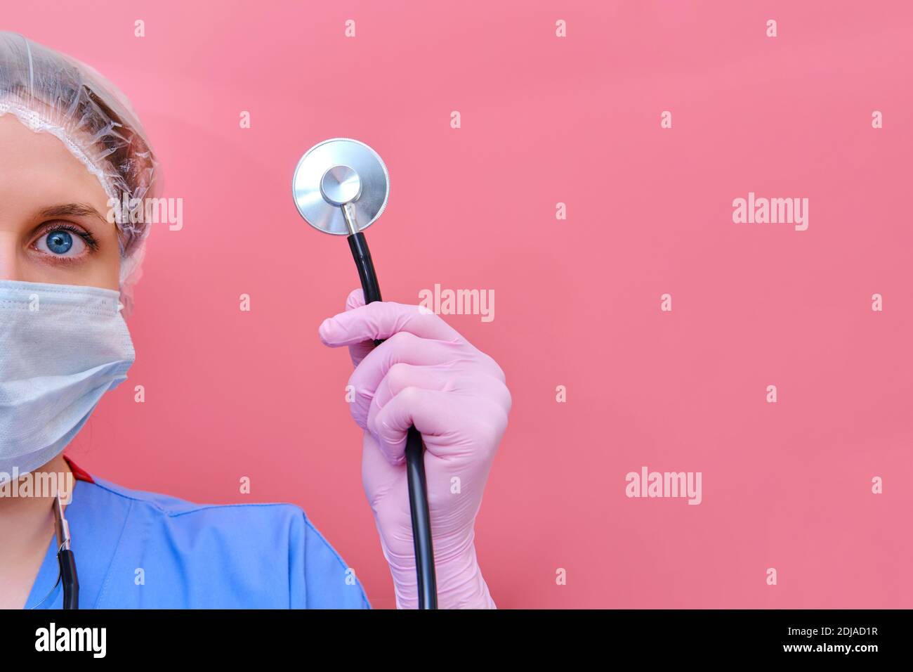 Doctor with a stethoscope in hand on a pink background, copy space for ...