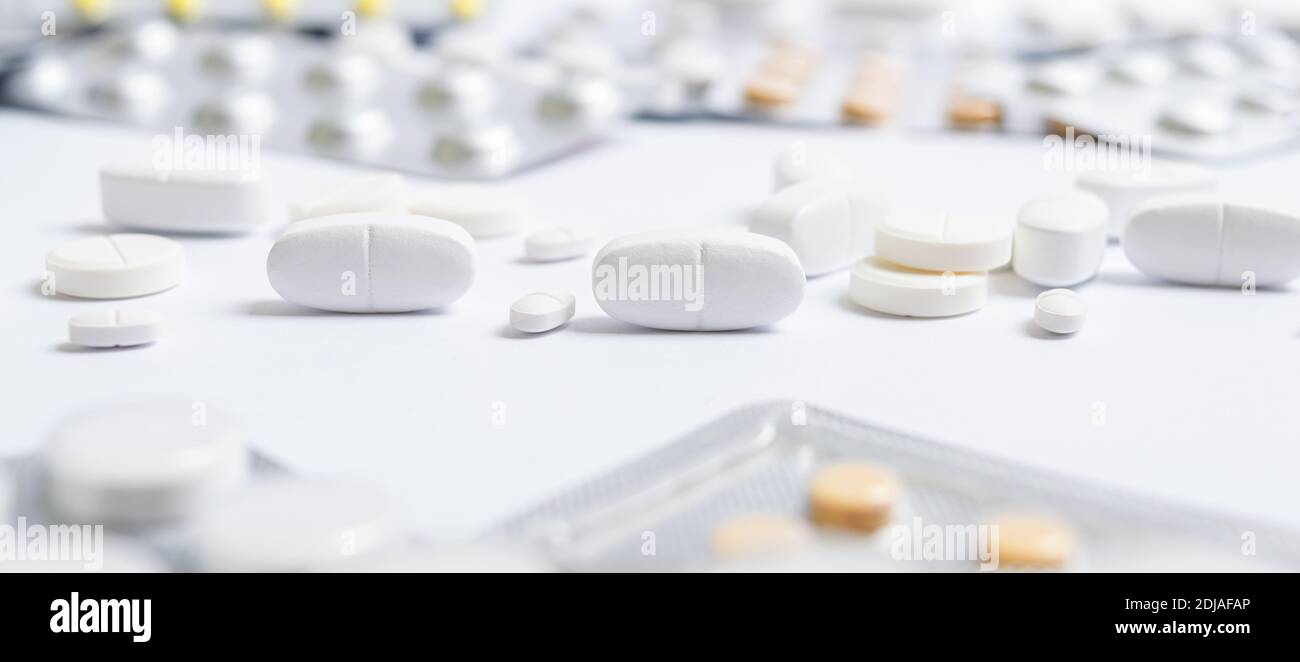 Heap of different pills, in blisters and scattered on white background ...