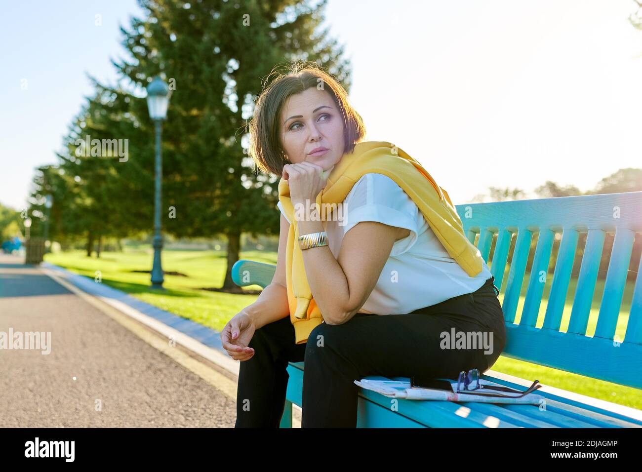 Tired sad mature woman sitting on bench in the park, copy space Stock ...