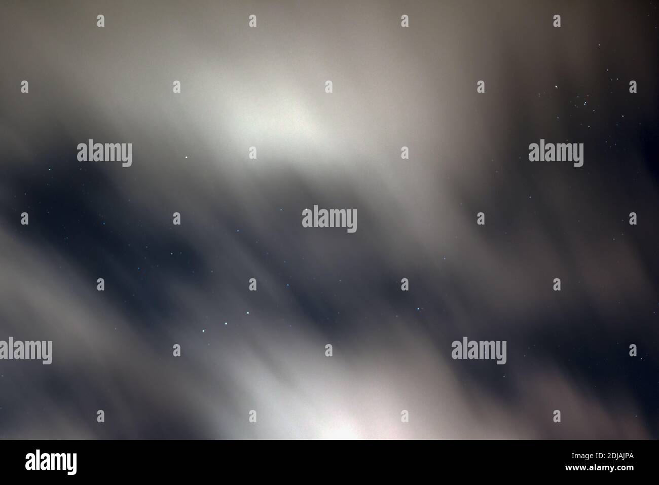 View of stars in a clear night sky with motion in clouds moving acroos ...