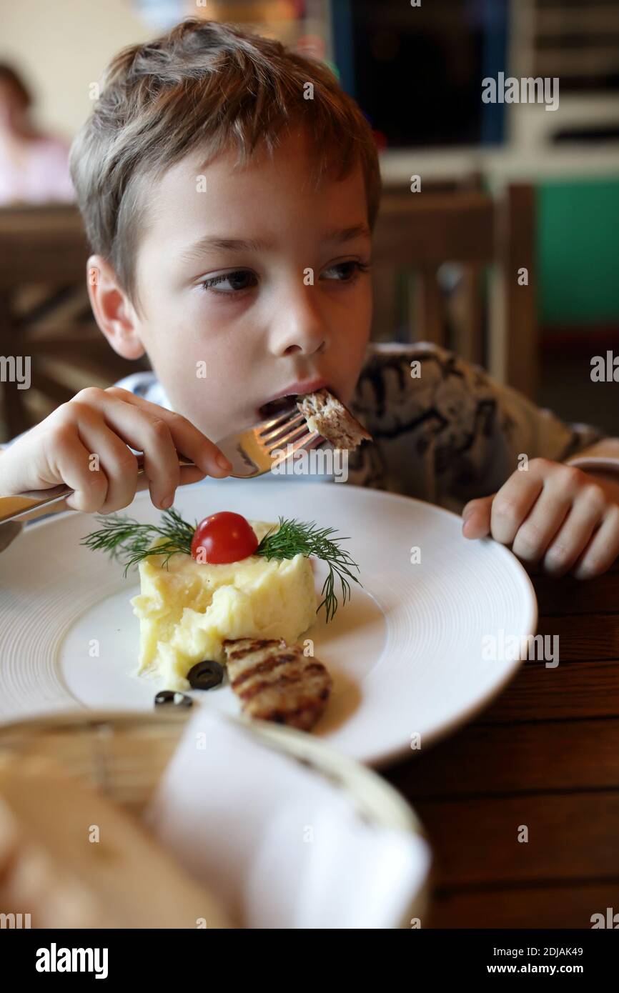 Kid eating cutlet at table in restaurant Stock Photo - Alamy