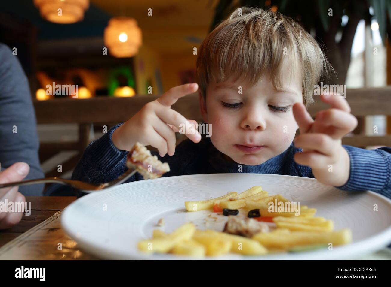 Child eating french fries in a restaurant Stock Photo - Alamy