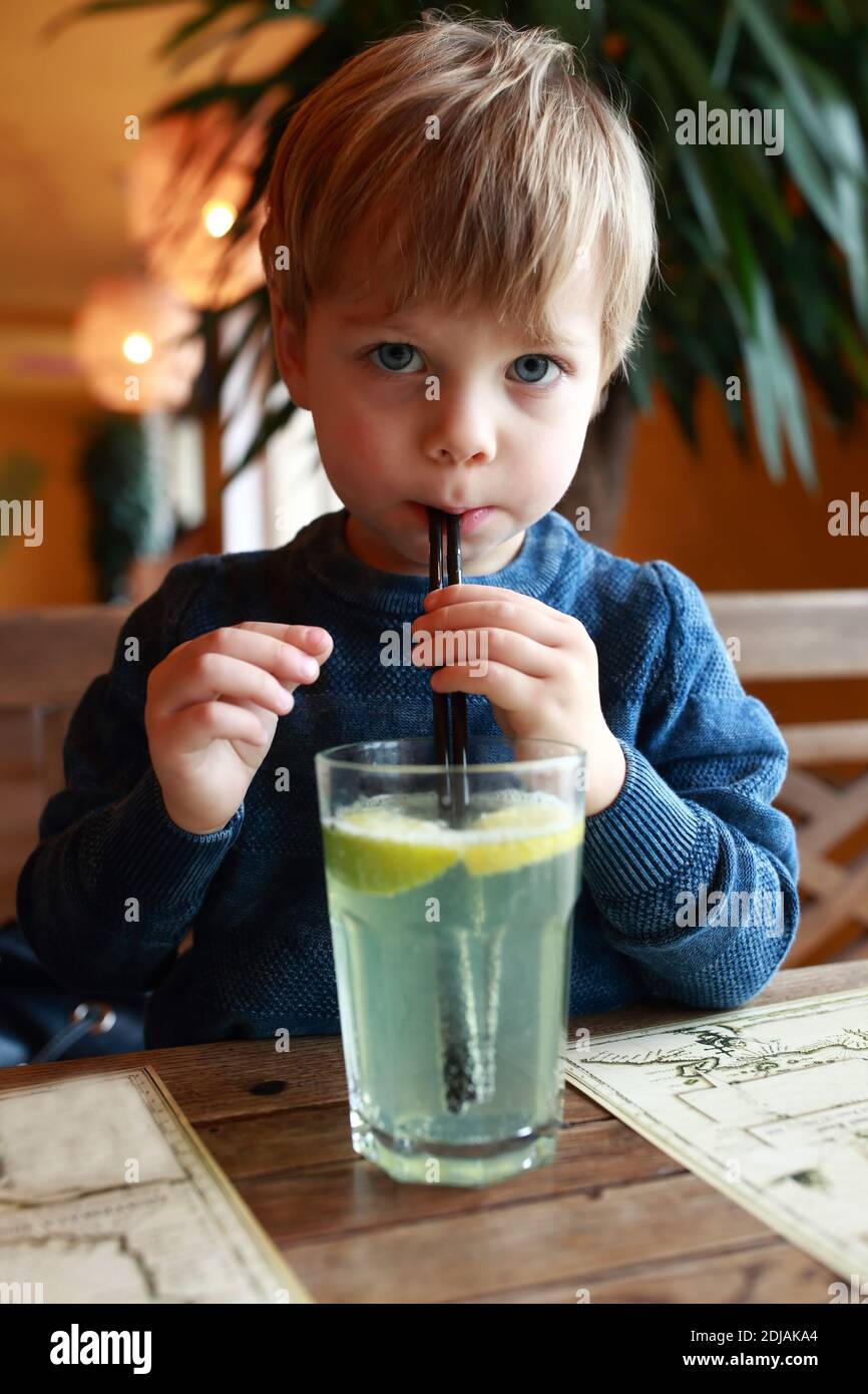 Boy drinking lemonade at table in cafe Stock Photo - Alamy