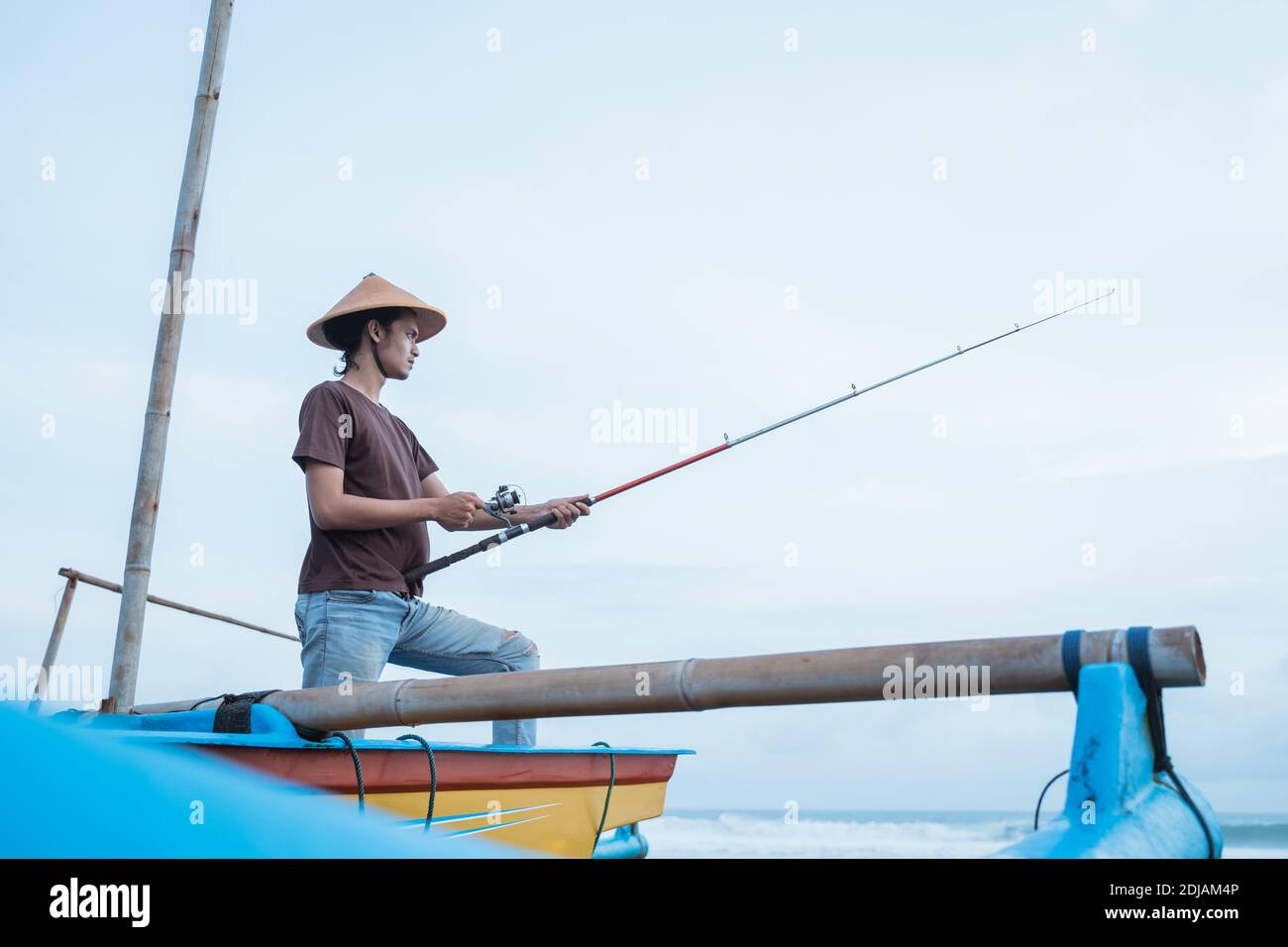 Portrait of a young fisherman fishing alone on a boat Stock Photo - Alamy