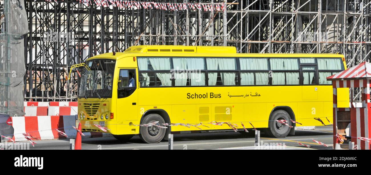 Dubai yellow school bus passing through scaffolding around bridge ...