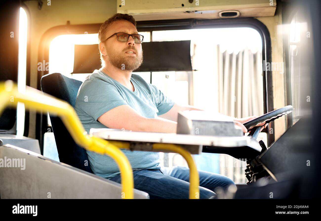 Focused and a bit worried bus driver is checking his side mirrors ...