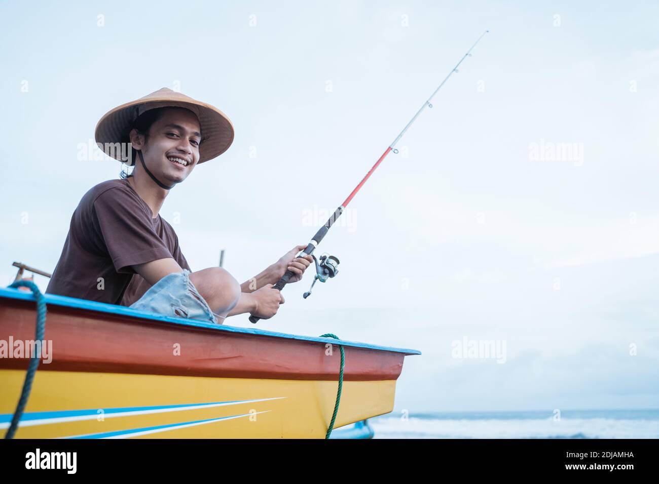 Portrait of a young fisherman fishing alone on a boat Stock Photo - Alamy