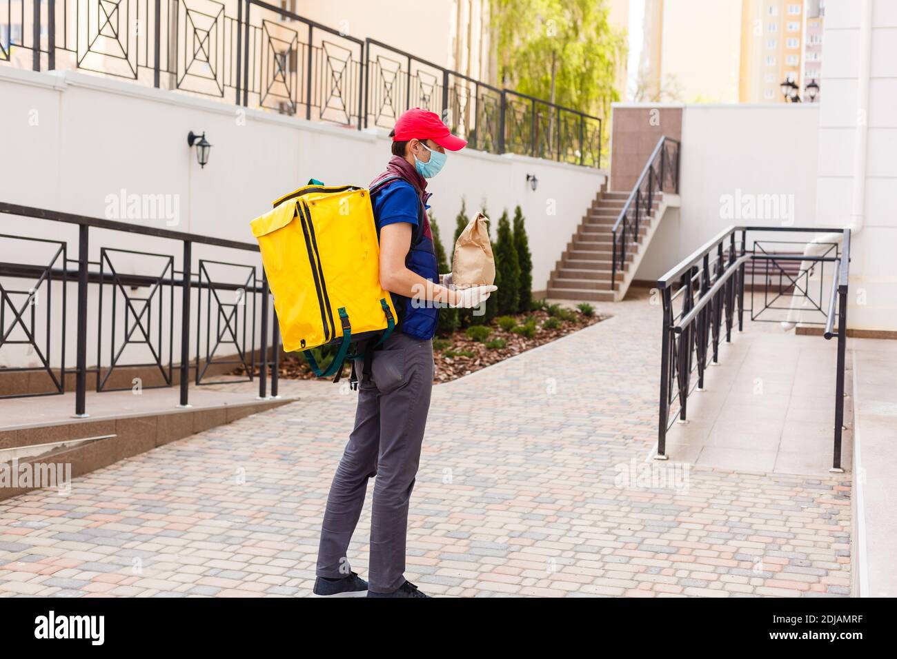 Portrait of a cheerful delivery man standing with yellow thermo ...