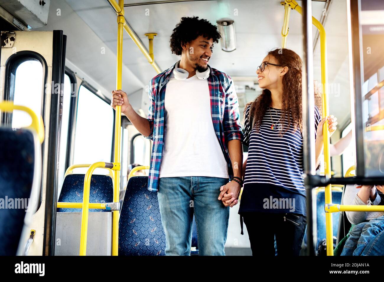 Young beautiful cheerful couple is standing in the middle of the bus ...
