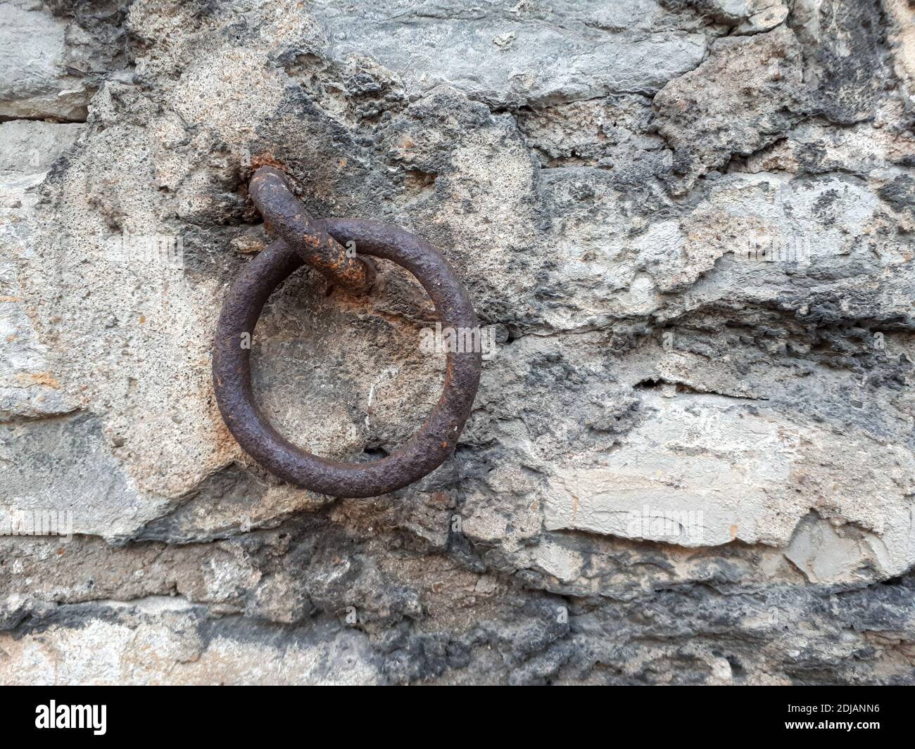 A closeup of a round rusty hook on a stone wall at daylight Stock Photo - Alamy